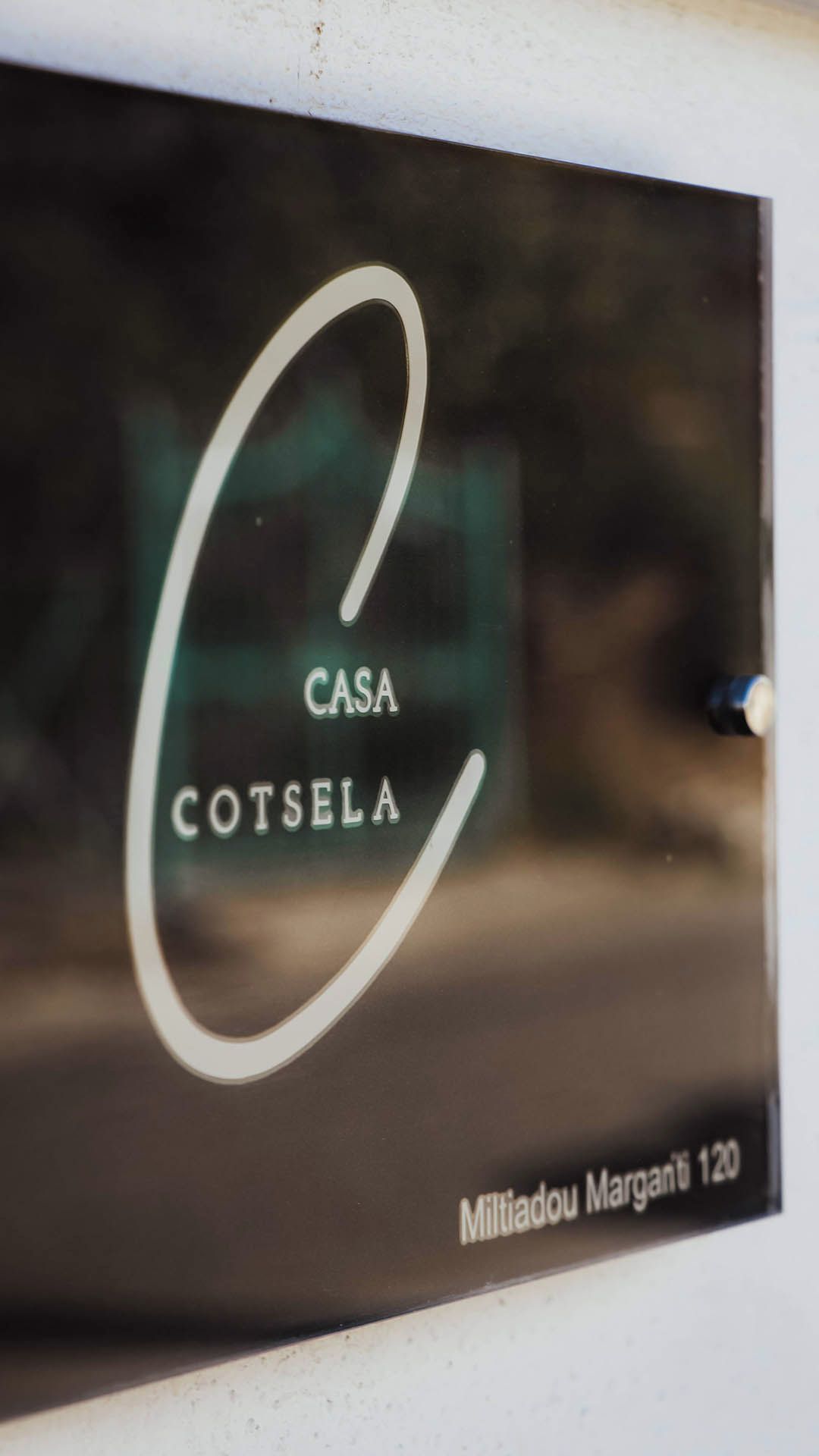 Placa com o texto 'CASA COTSELA' e 'Miliadou Margani 120'.