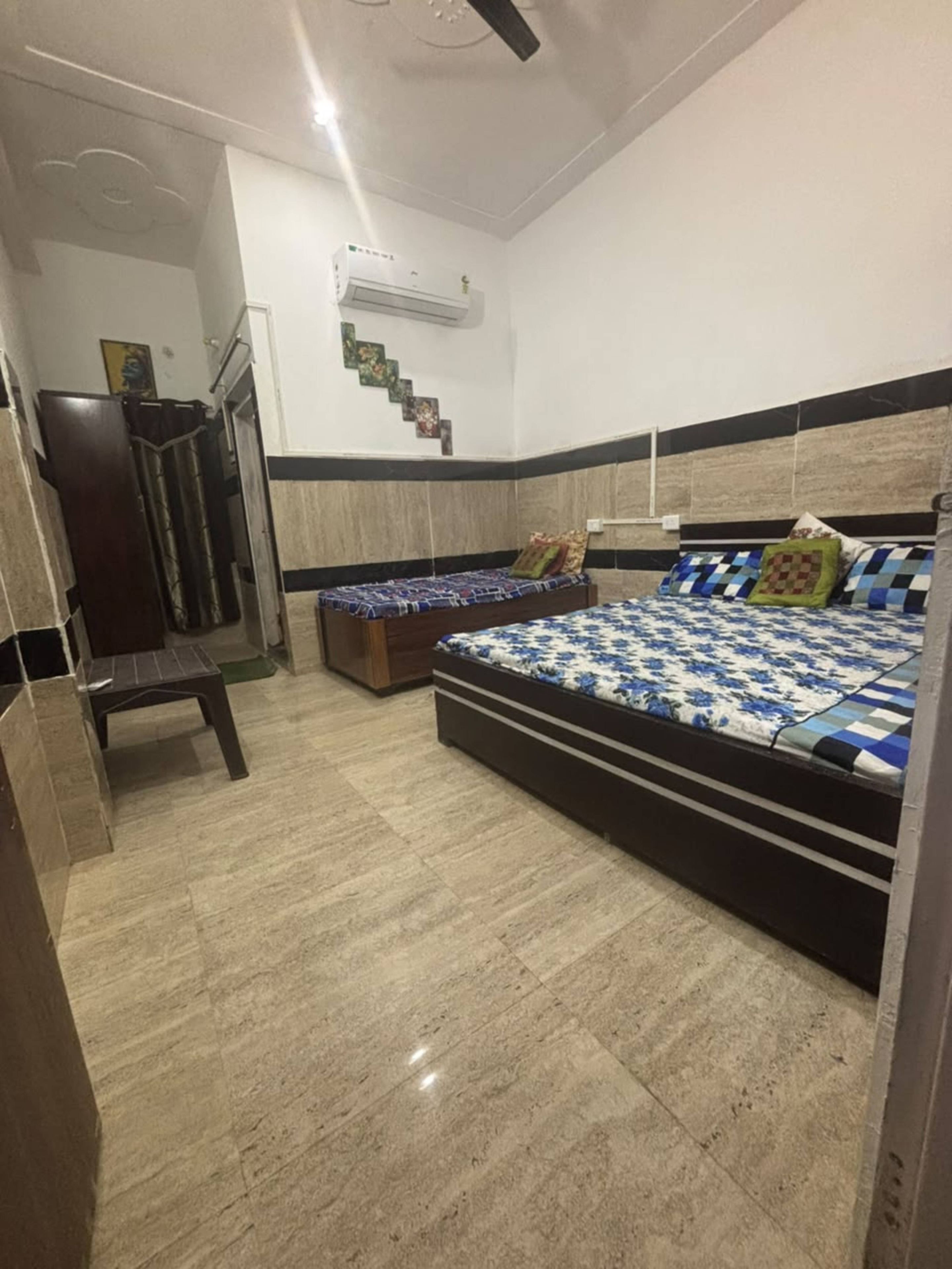 Um quarto com cama, uma mesinha e um guarda-roupa.