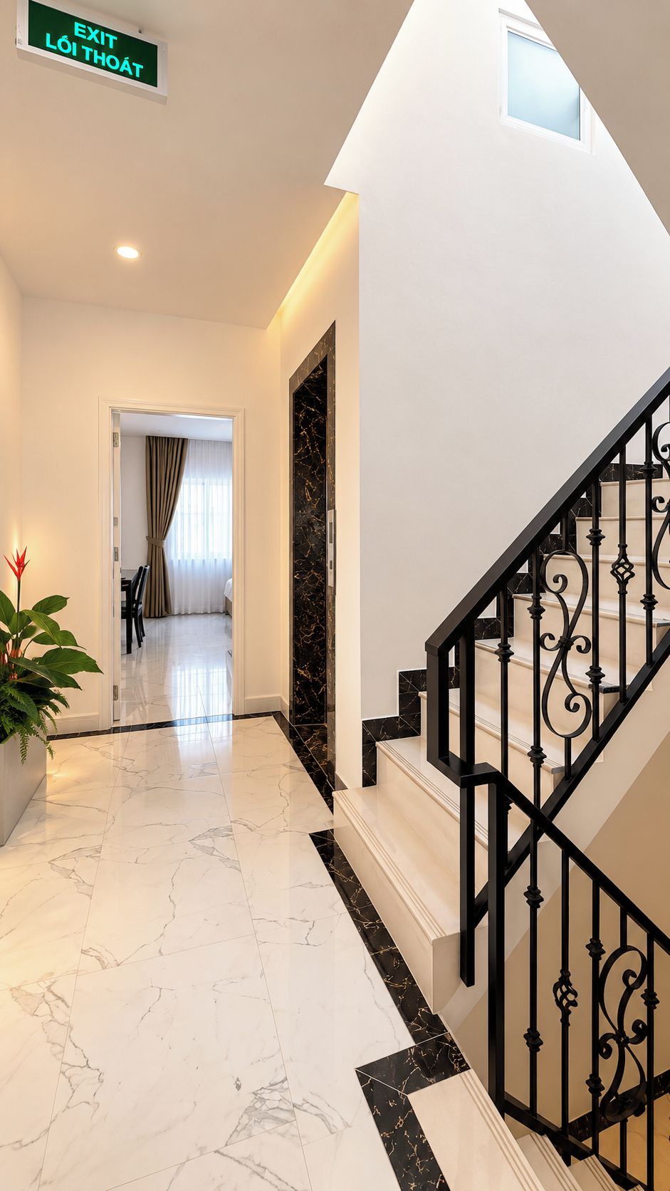 Corredor de hotel com piso de mármore, escada com corrimão preto e placa de saída.