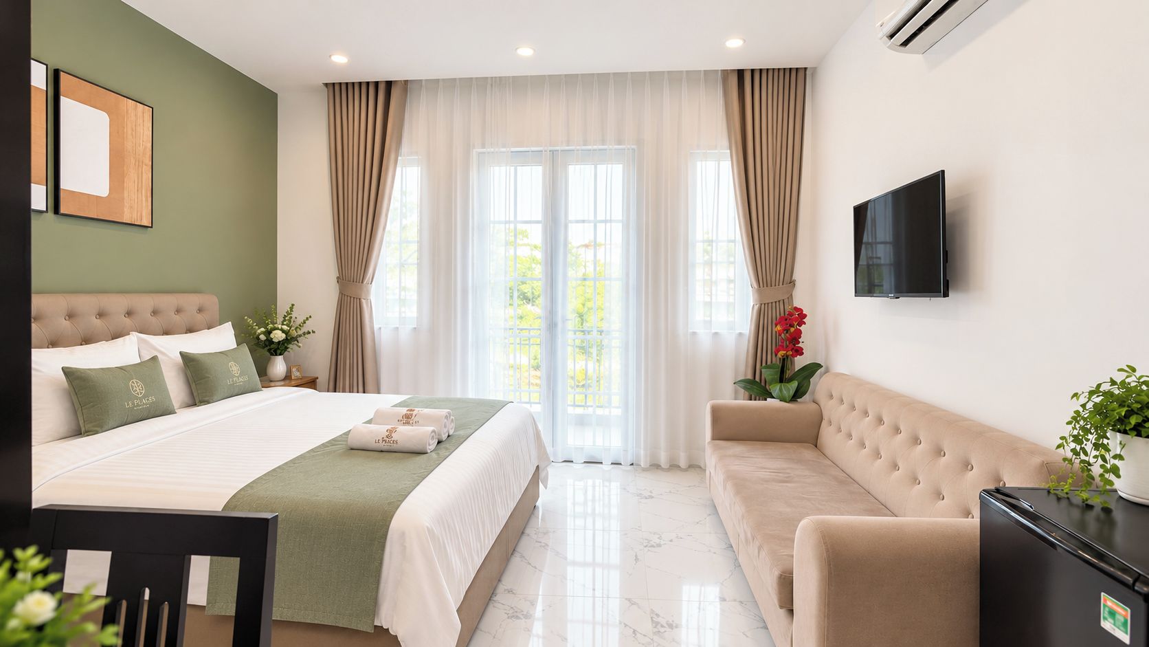 Quarto de hotel com cama, sofá, televisão e escrivaninha.