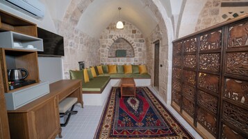 Quarto aconchegante com parede de pedra, sofá verde, armário de madeira e painel decorativo com esculturas de animais.
