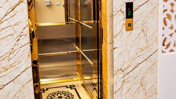 Um elevador com parede de mármore e interior dourado.