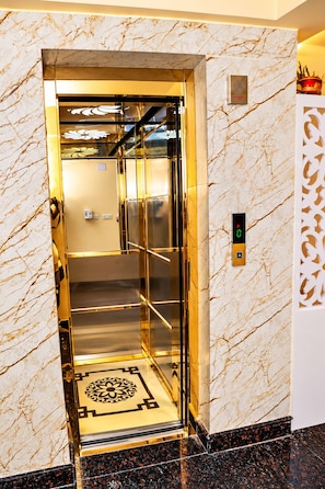 Um elevador com parede de mármore e interior dourado.