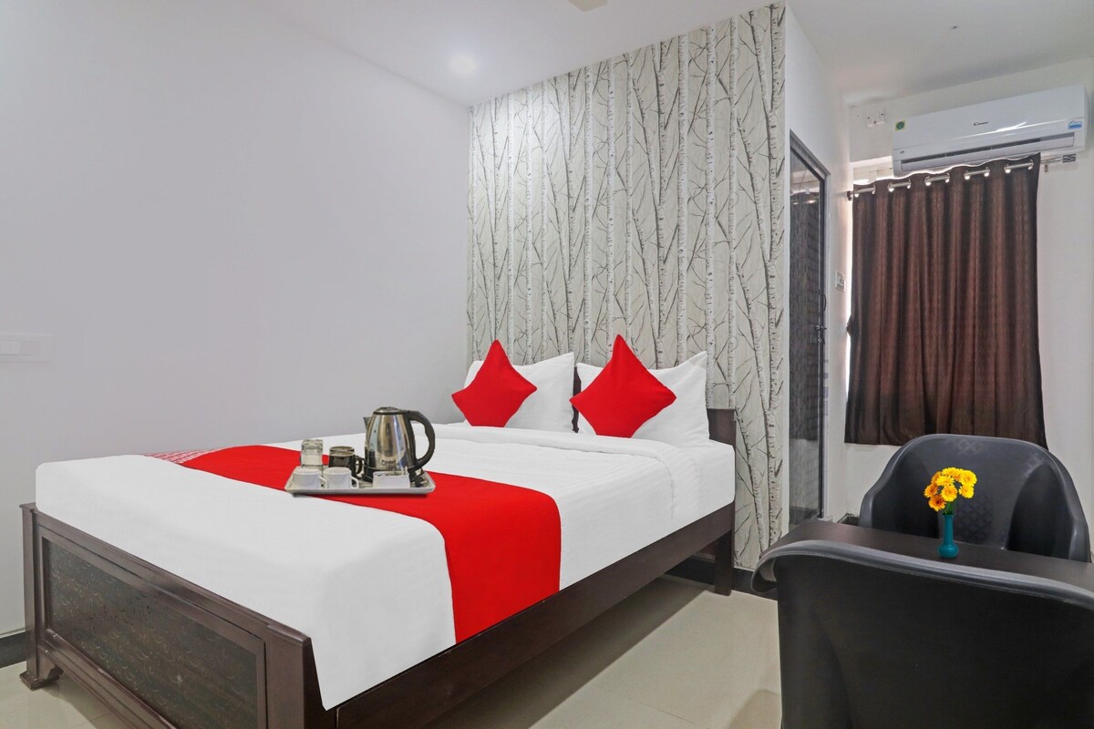 Quarto de hotel com cama, cafeteira e uma cadeira.