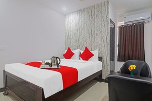 Quarto de hotel com cama, cafeteira e uma cadeira.