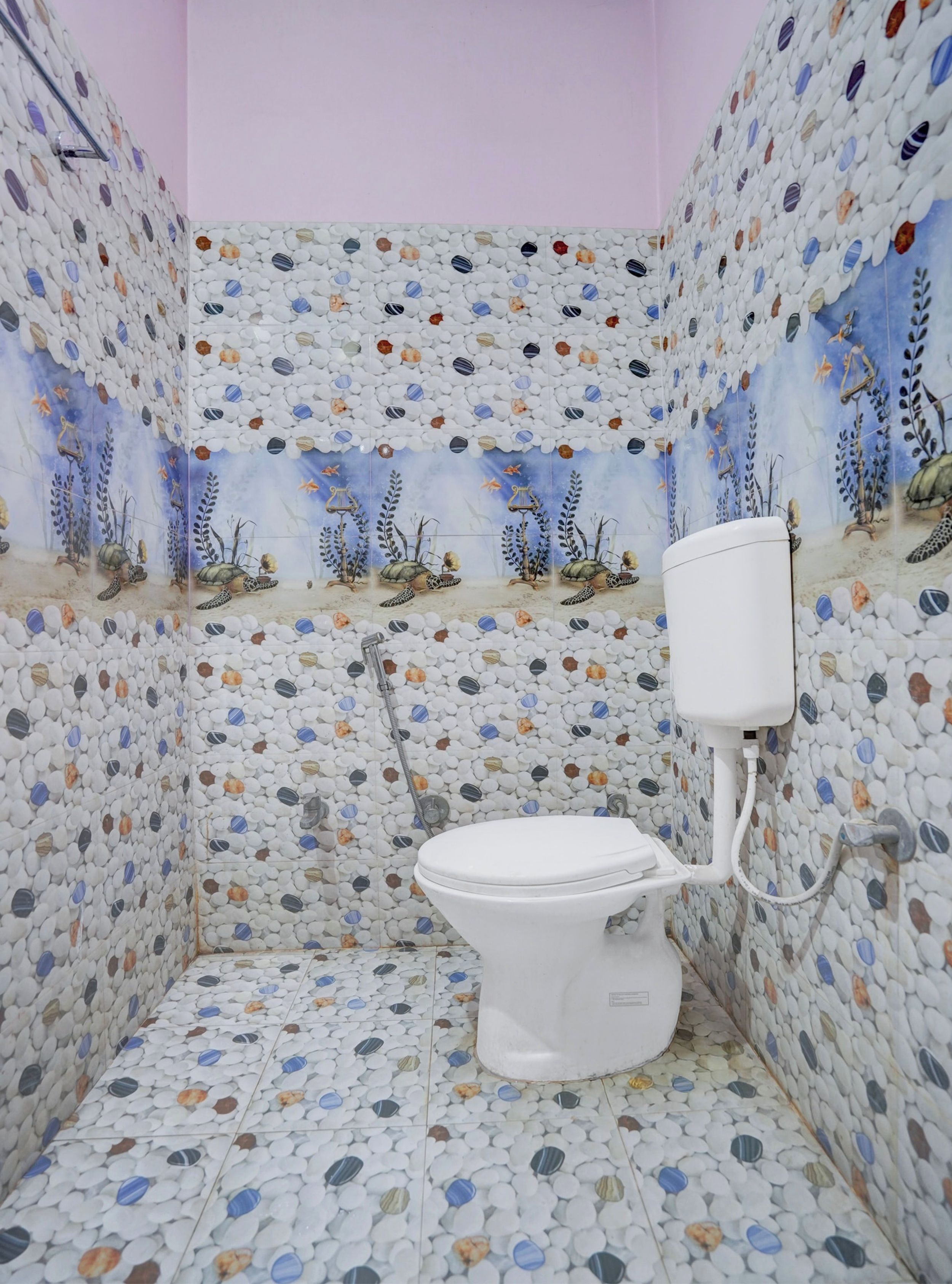 Casa de banho com sanita branca, chuveiro e paredes revestidas com azulejos tipo pedra.