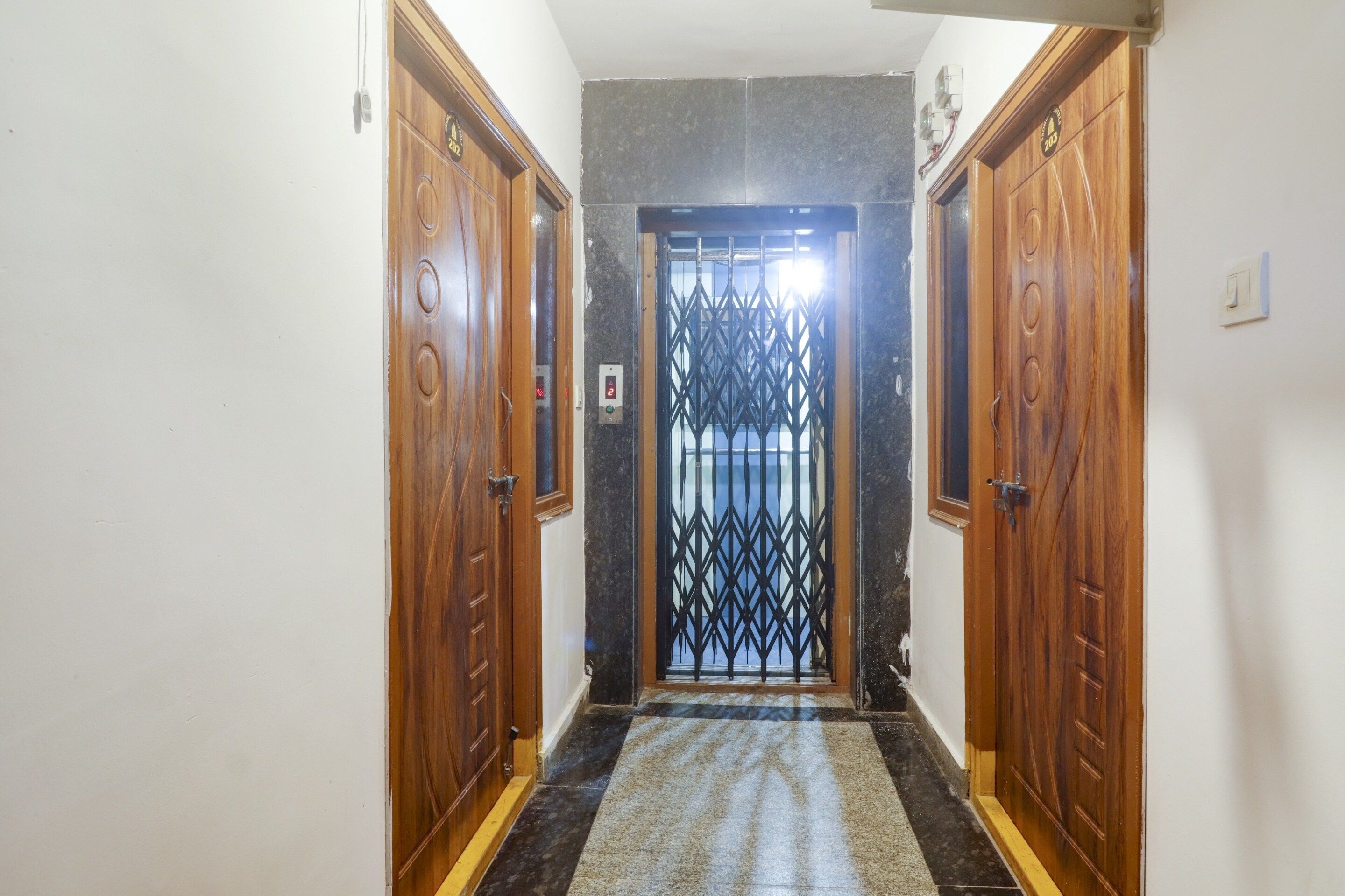 Um corredor com portas de madeira e um portão de metal no final.