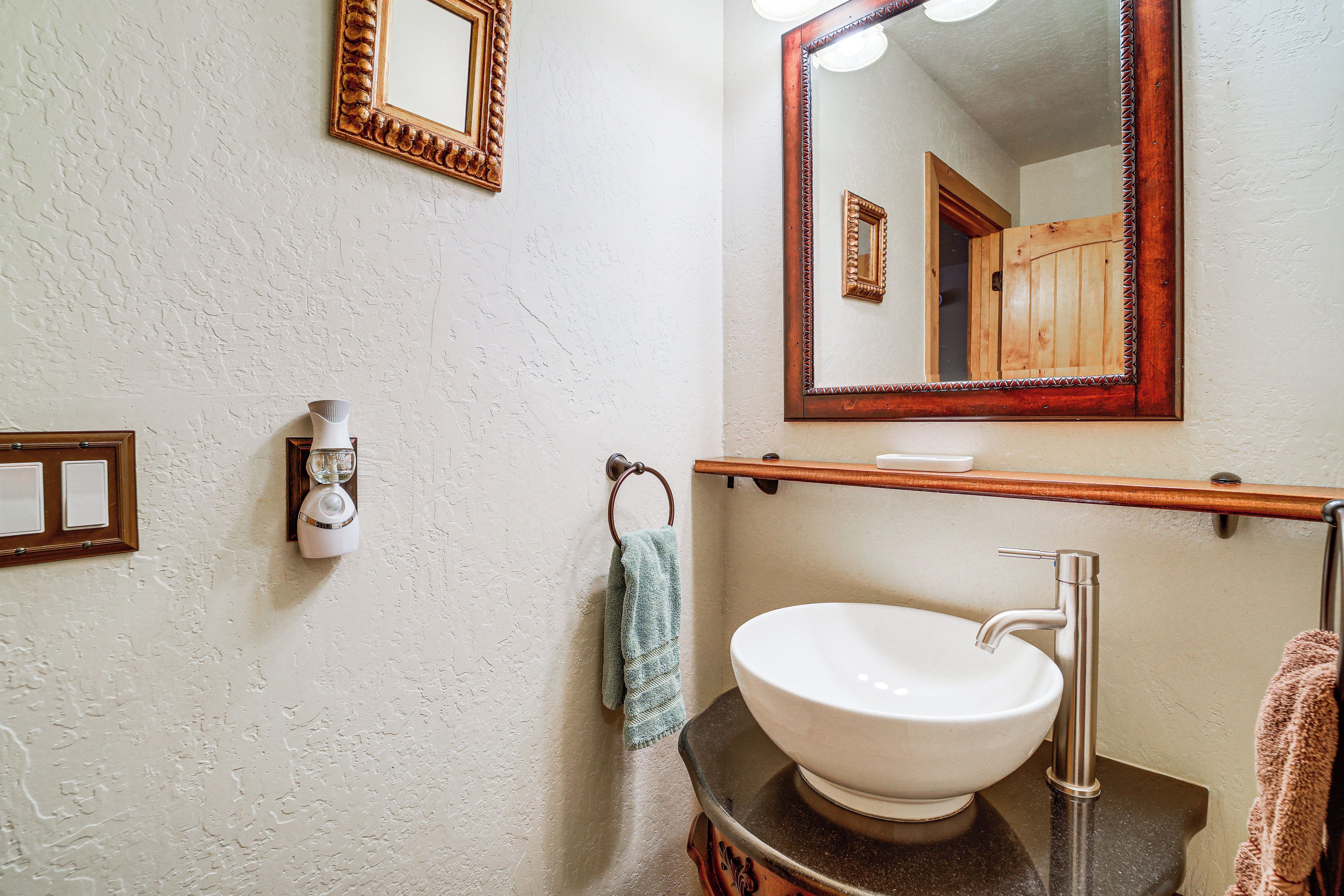 Casa de banho com lavatório branco, espelho e porta-toalhas.