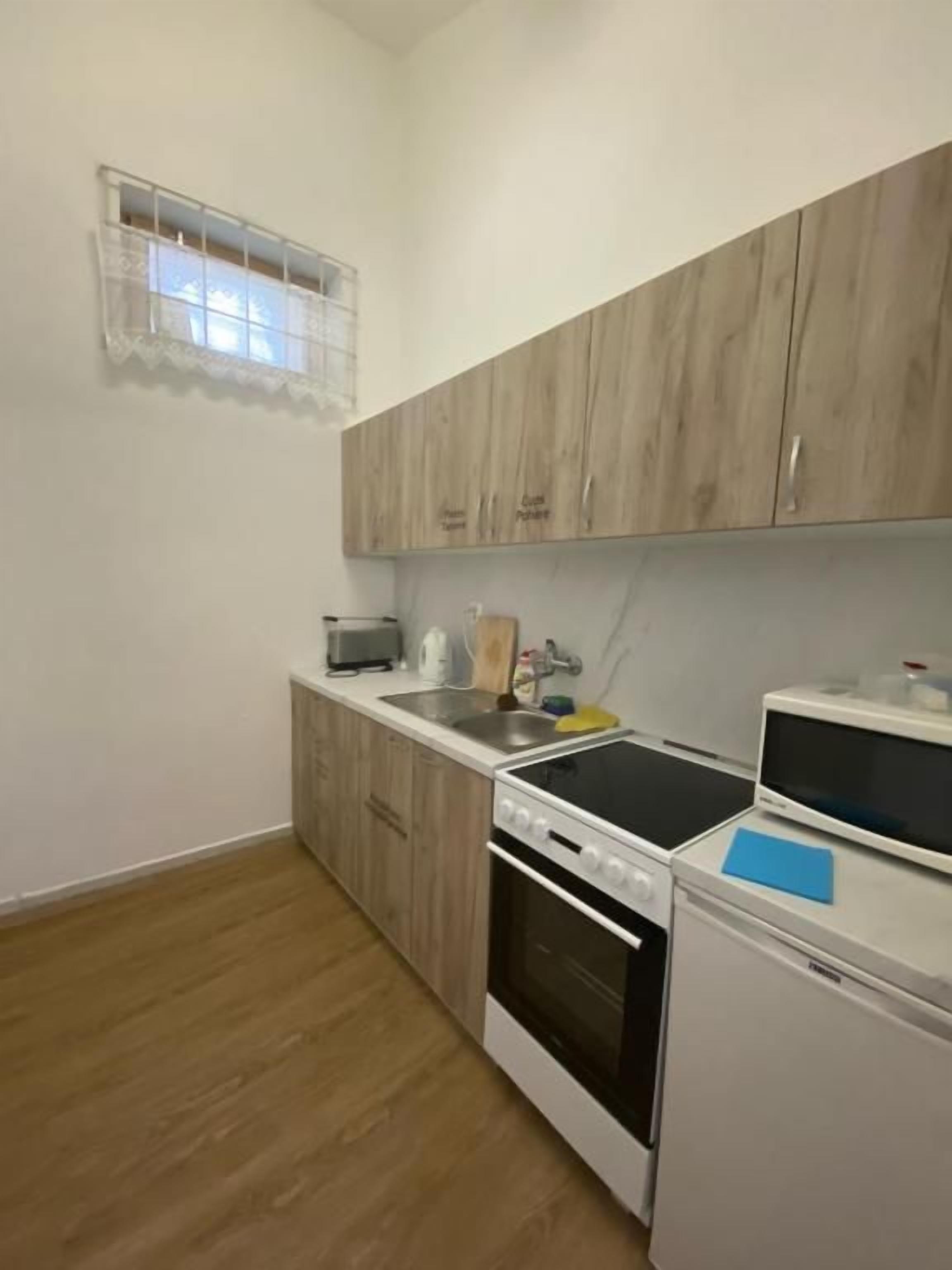 Cozinha compacta com armários de madeira, forno embutido, micro-ondas e pia.