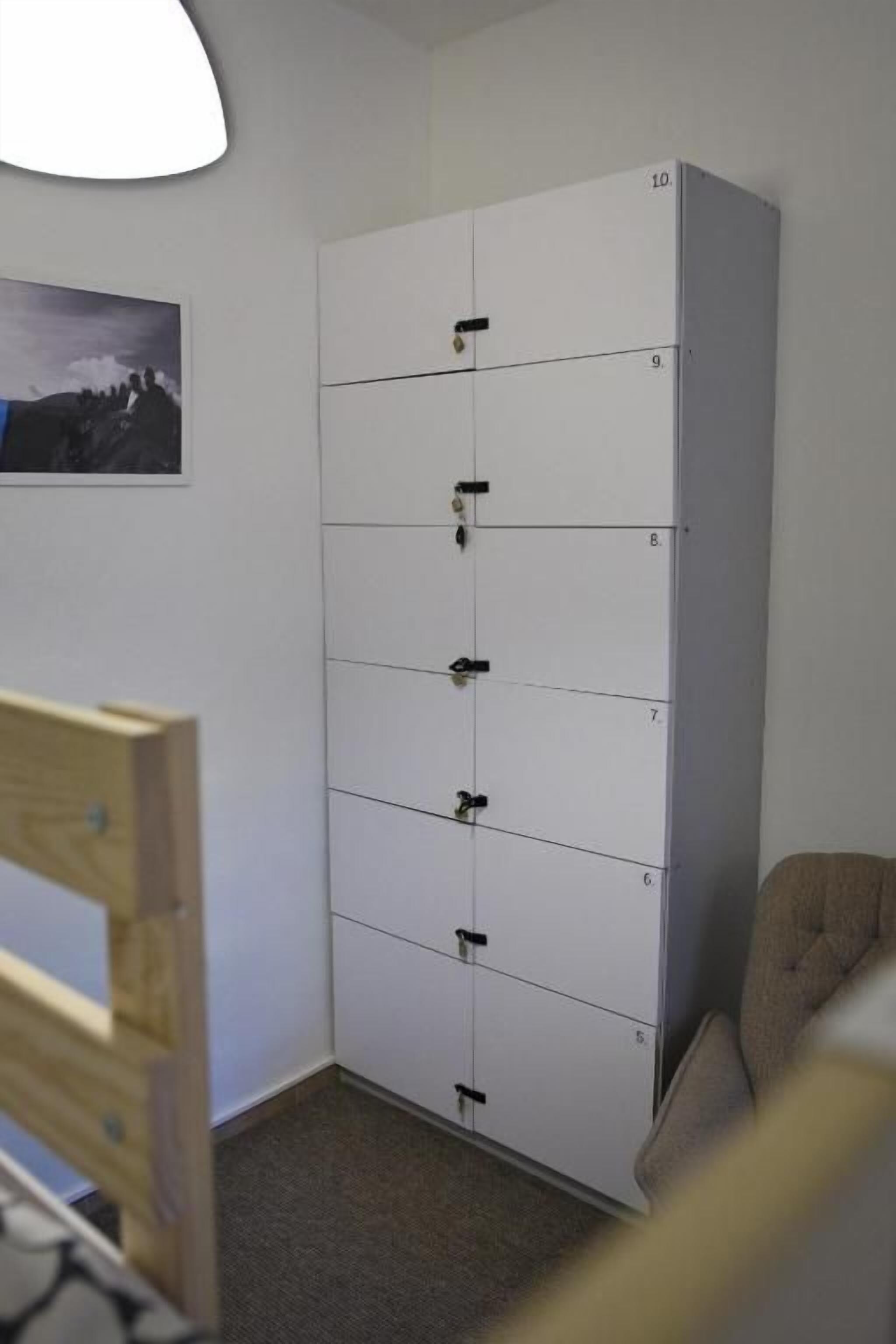 Um armazém branco com vários compartimentos, um quadro na parede e uma cadeira no canto.