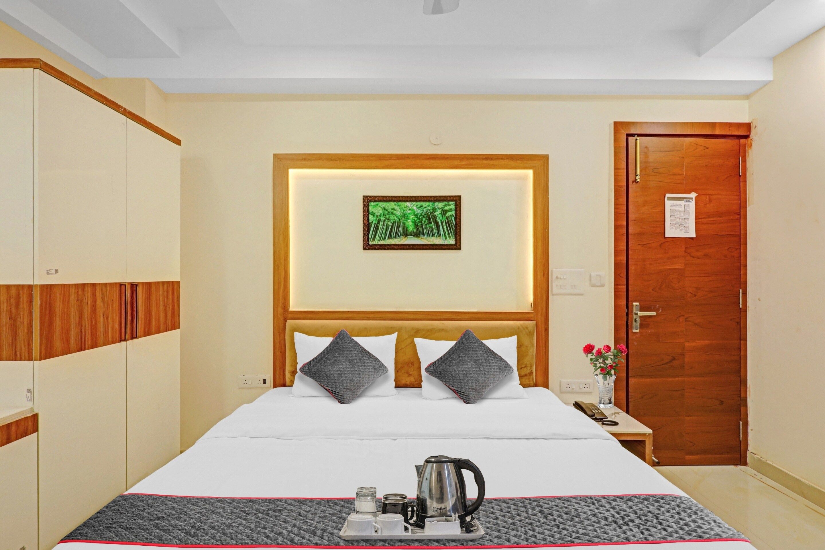 Quarto de hotel com cama, mesa de cabeceira e porta.