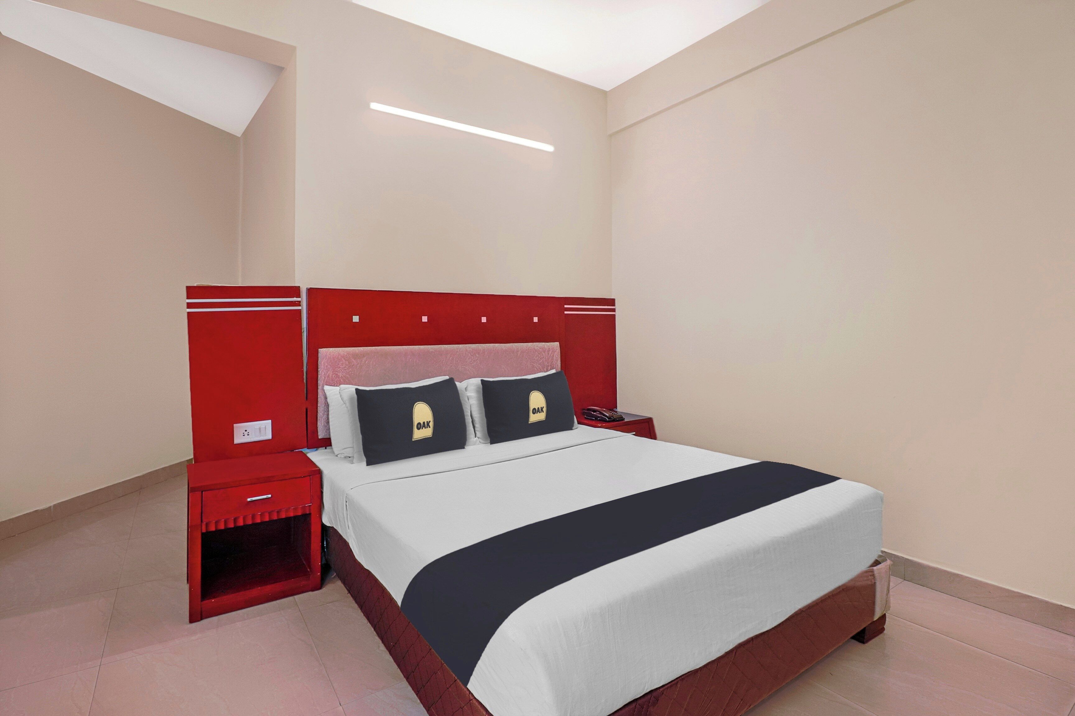 Quarto de hotel com cama, mesa de cabeceira e parede vermelha.