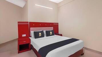 Quarto de hotel com cama, mesa de cabeceira e parede vermelha.