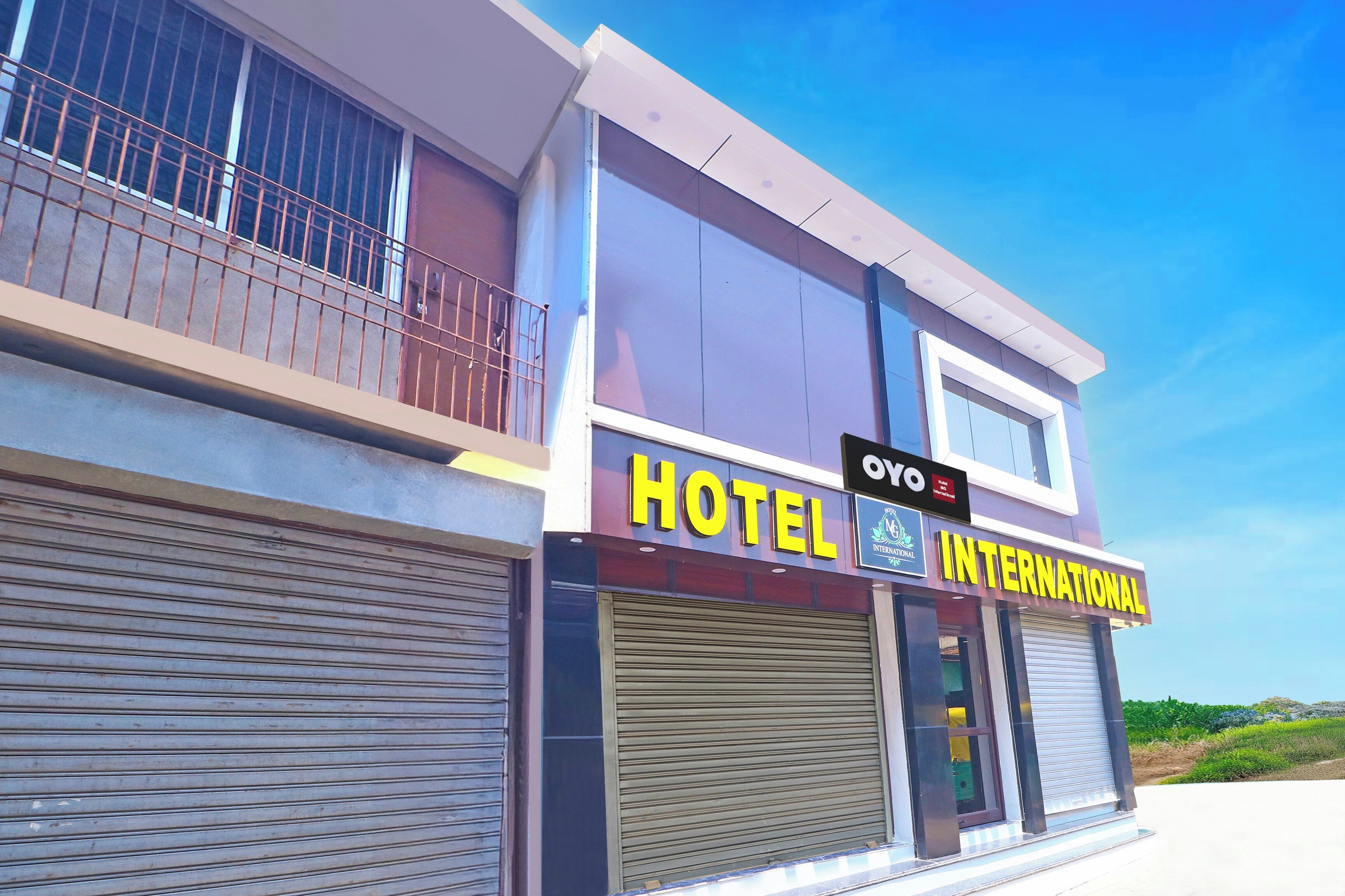 Hotel com venezianas fechadas, varanda e sinalização indicando ser um hotel internacional.