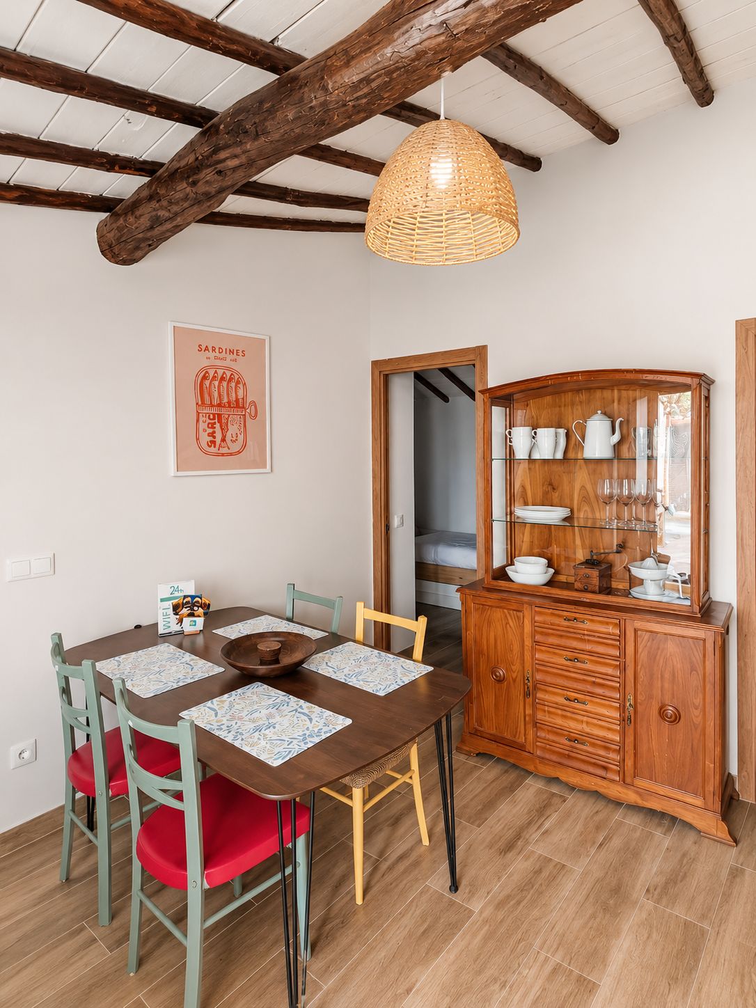 Uma área de refeições com mesa de madeira, cadeiras e um armário com louças.