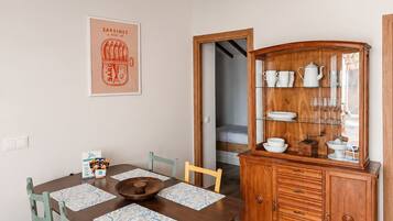 Uma área de refeições com mesa de madeira, cadeiras e um armário com louças.