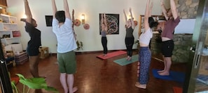 Um grupo de pessoas em uma sala com piso de madeira, parede de pedra e um quadro na parede.