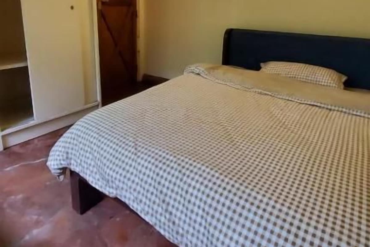 Quarto com cama, luminária na parede e uma porta.
