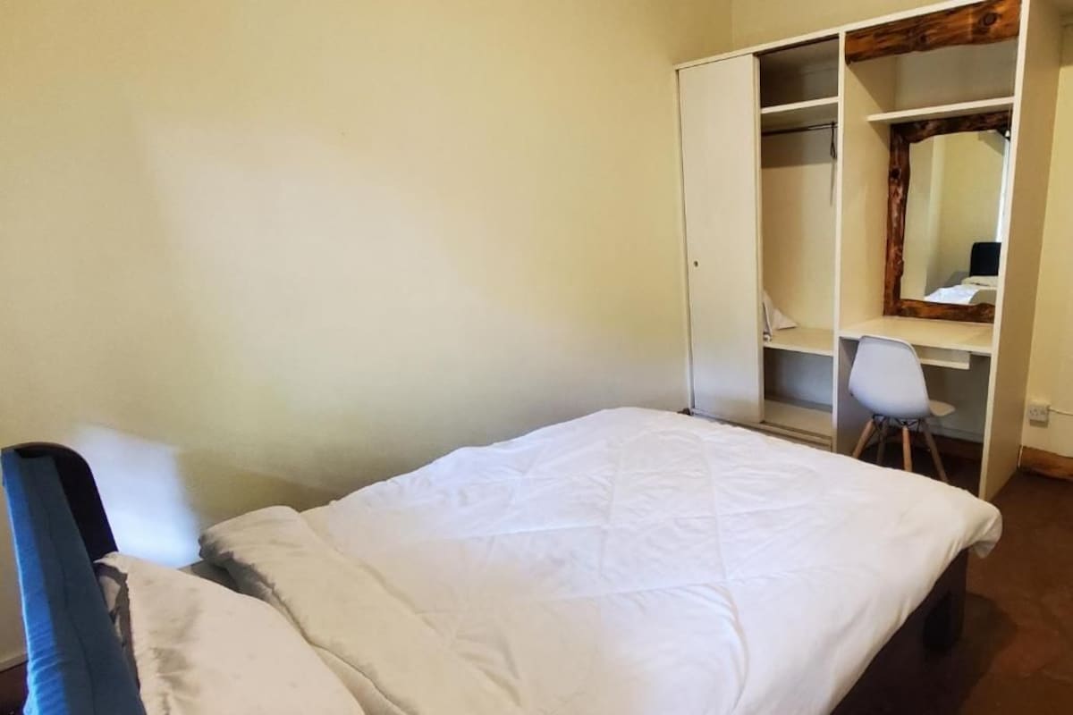 Quarto com cama, cadeira, guarda-roupa e espelho.