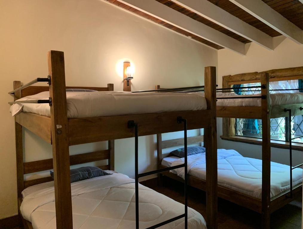 Quarto com beliche, teto de madeira e luminária fixada na parede.