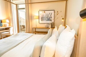 Quarto de hotel com cama, mesa de cabeceira, luminária e um quadro na parede.