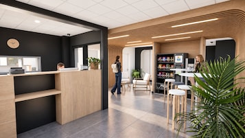 Uma área de recepção moderna com balcão de madeira, espaço de estar e máquina de vendas automática.