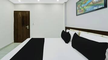 Quarto com cama, porta, quadro na parede e luminária no teto.