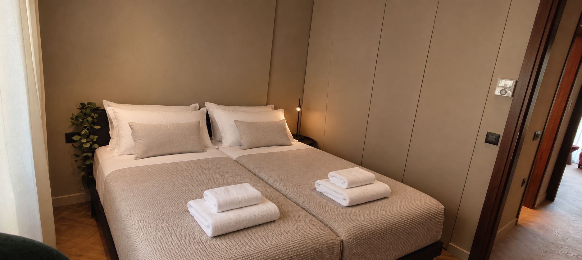 Cama de casal com duas almofadas e duas toalhas dobradas.