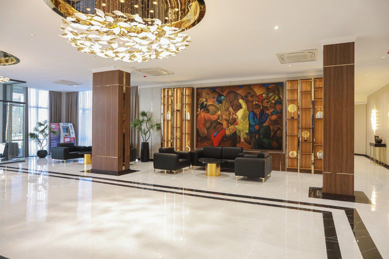 Um saguão de hotel com um grande mural, área de estar e um lustre moderno.