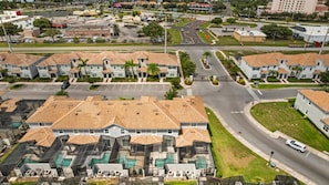 Um bairro residencial com edifícios de vários andares, uma rua central e um estacionamento.