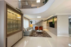 Um interior moderno com uma vitrine de vidro, uma escada, um sofá e uma mesa de centro.