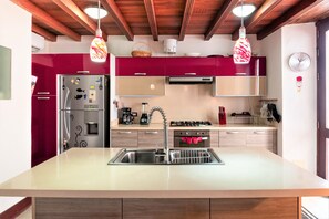 Cozinha moderna com ilha central, eletrodomésticos de aço inoxidável e uma parede de destaque vermelha.