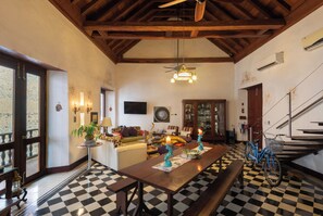 Uma sala de estar ampla com piso xadrez, uma mesa de jantar e uma escada.