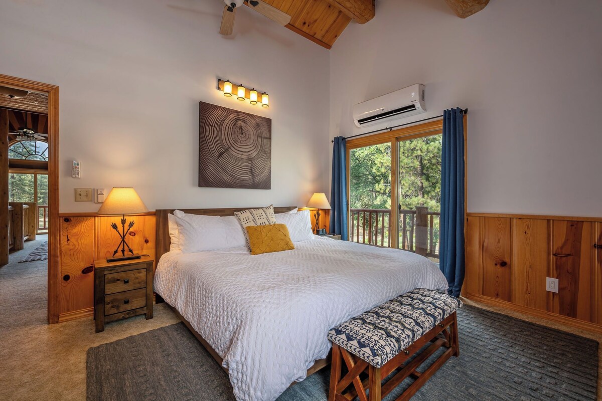 Quarto com cama grande, abajures, obra de arte na parede e ar condicionado.