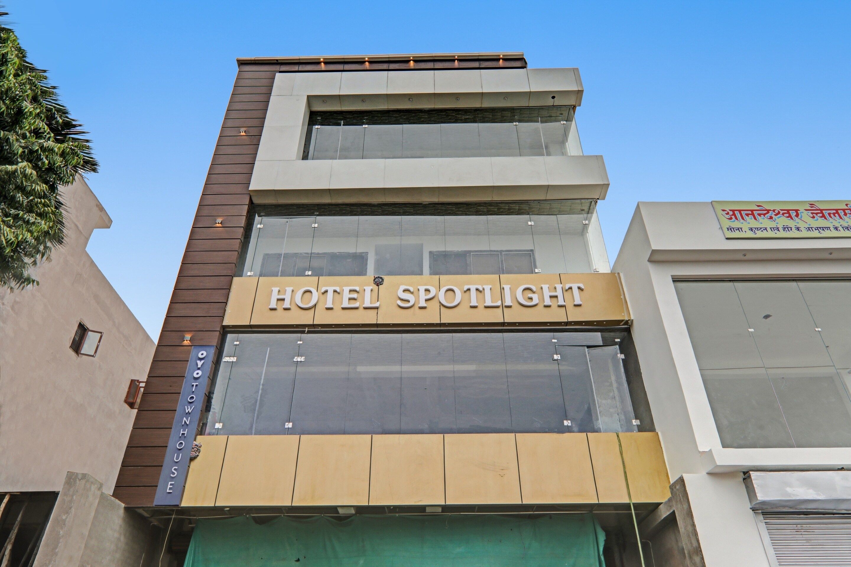 Um hotel chamado 'HOTEL SPOTLIGHT' com fachada moderna, grandes janelas e uma placa indicando 'YOTOWHOUSE'.