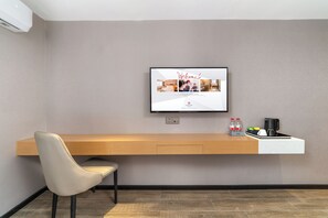 Uma área de recepção de hotel moderna, com uma mesa de madeira, uma poltrona acolchoada e um quadro com a mensagem de boas-vindas.
