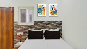 Quarto com cama, porta de madeira, janela e duas pinturas abstratas na parede.