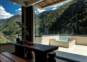 Uma varanda com piscina, mesa de jantar e vista para uma cordilheira arborizada.