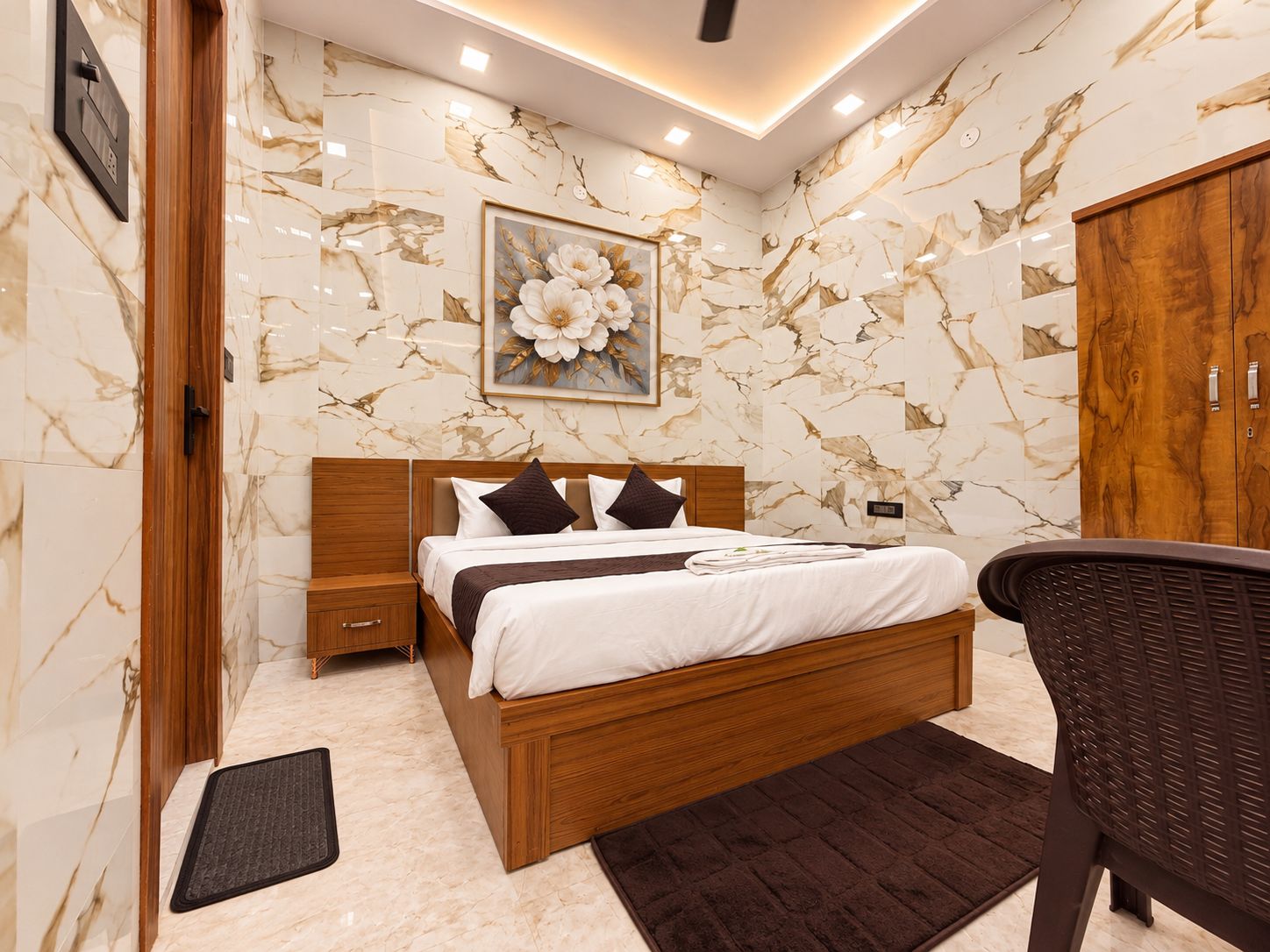 Quarto com cama de madeira, paredes de mármore, uma pintura floral grande e um guarda-roupa de madeira.