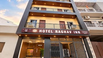 Hotel com vários andares, área de recepção, varandas e placa indicando quartos disponíveis.