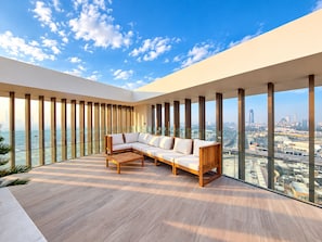 Sala de estar moderna com um amplo sofá modular, mesa de centro de madeira e janelas do chão ao teto com vista para a cidade.