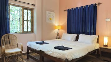 Quarto com cama, cadeira, janela com cortinas, luminária na parede e um pôster.