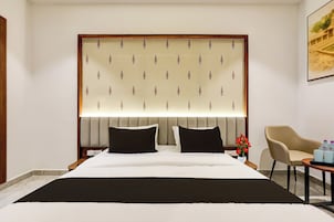 Quarto de hotel com uma cama grande, duas mesas de cabeceira, uma cadeira e um quadro na parede.