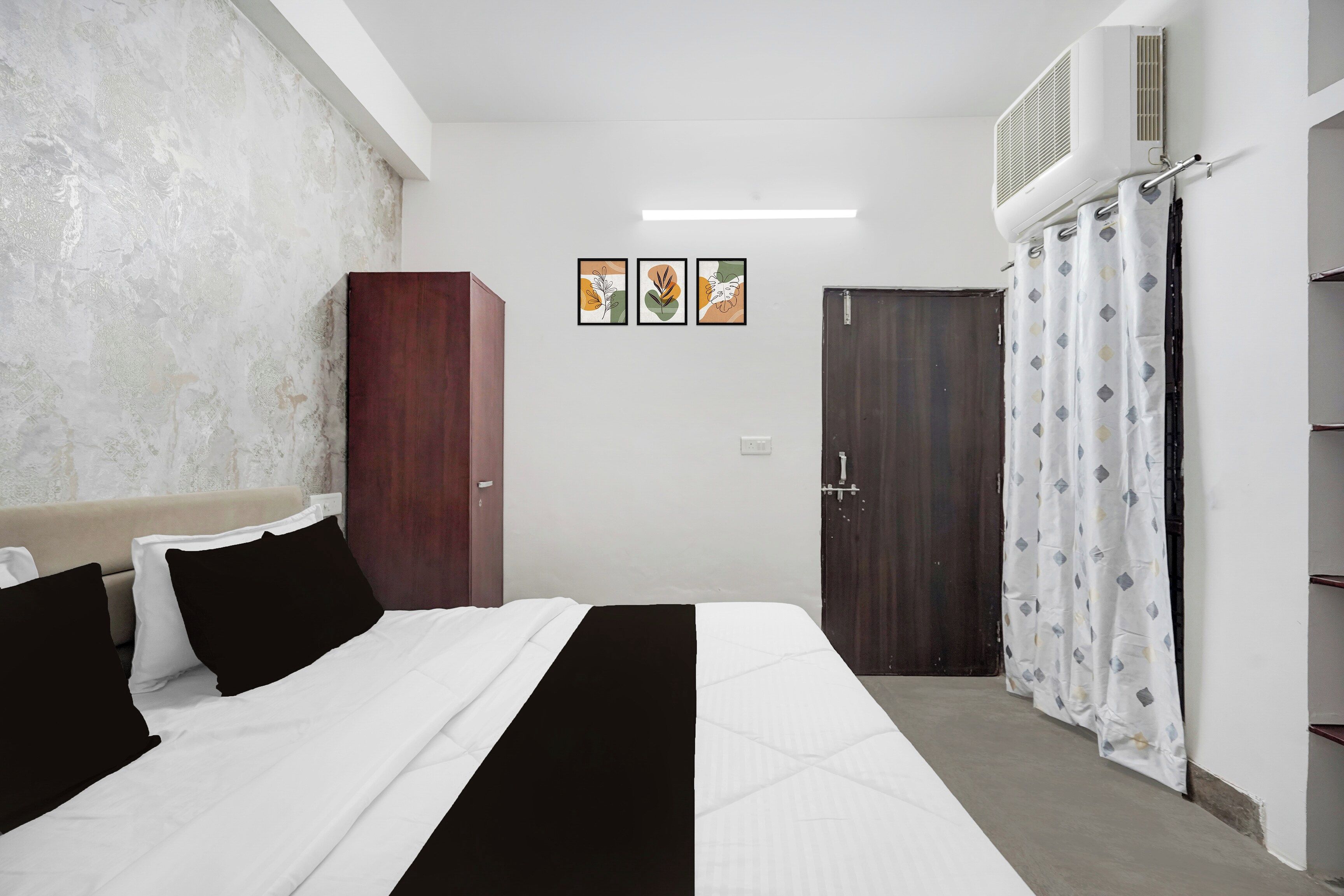 Quarto com cama, guarda-roupa, porta e ar-condicionado fixado na parede.