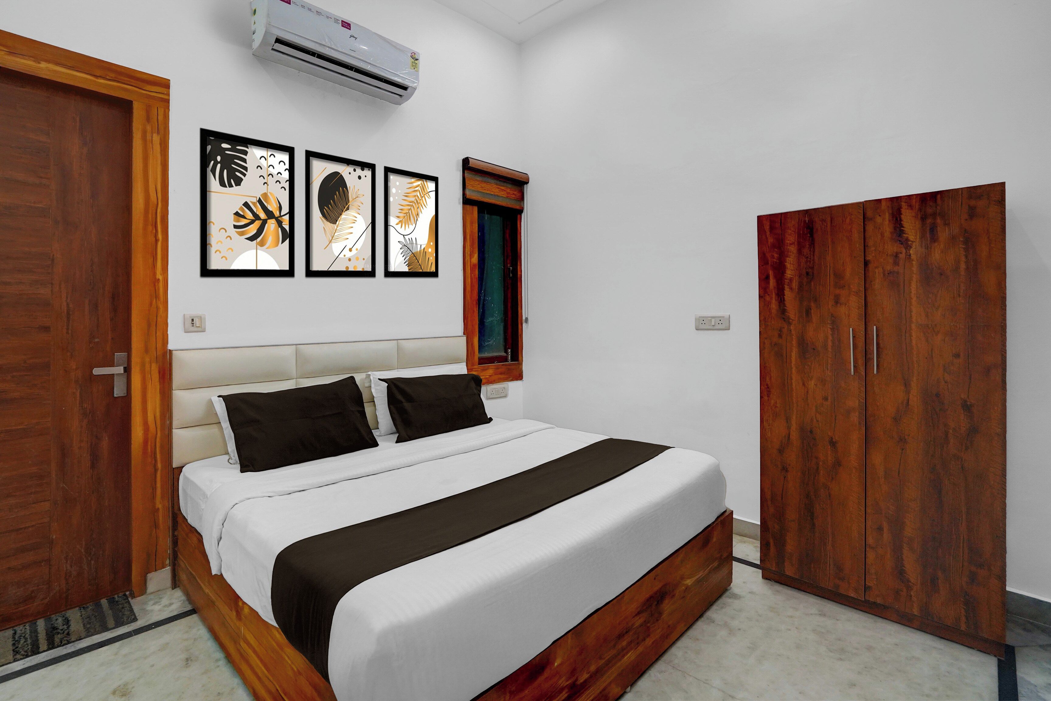 Quarto com cama, guarda-roupa de madeira e três obras de arte emolduradas na parede.