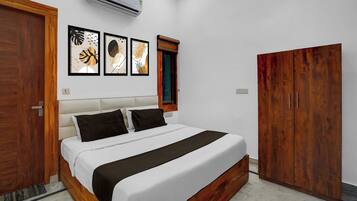 Quarto com cama, guarda-roupa de madeira e três obras de arte emolduradas na parede.