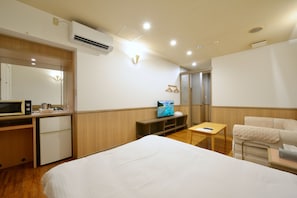 Quarto de hotel com cama, escrivaninha, televisão e banheiro.