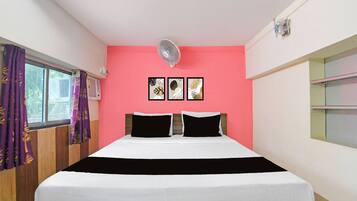 Quarto com cama, janela com cortinas e três quadros na parede.