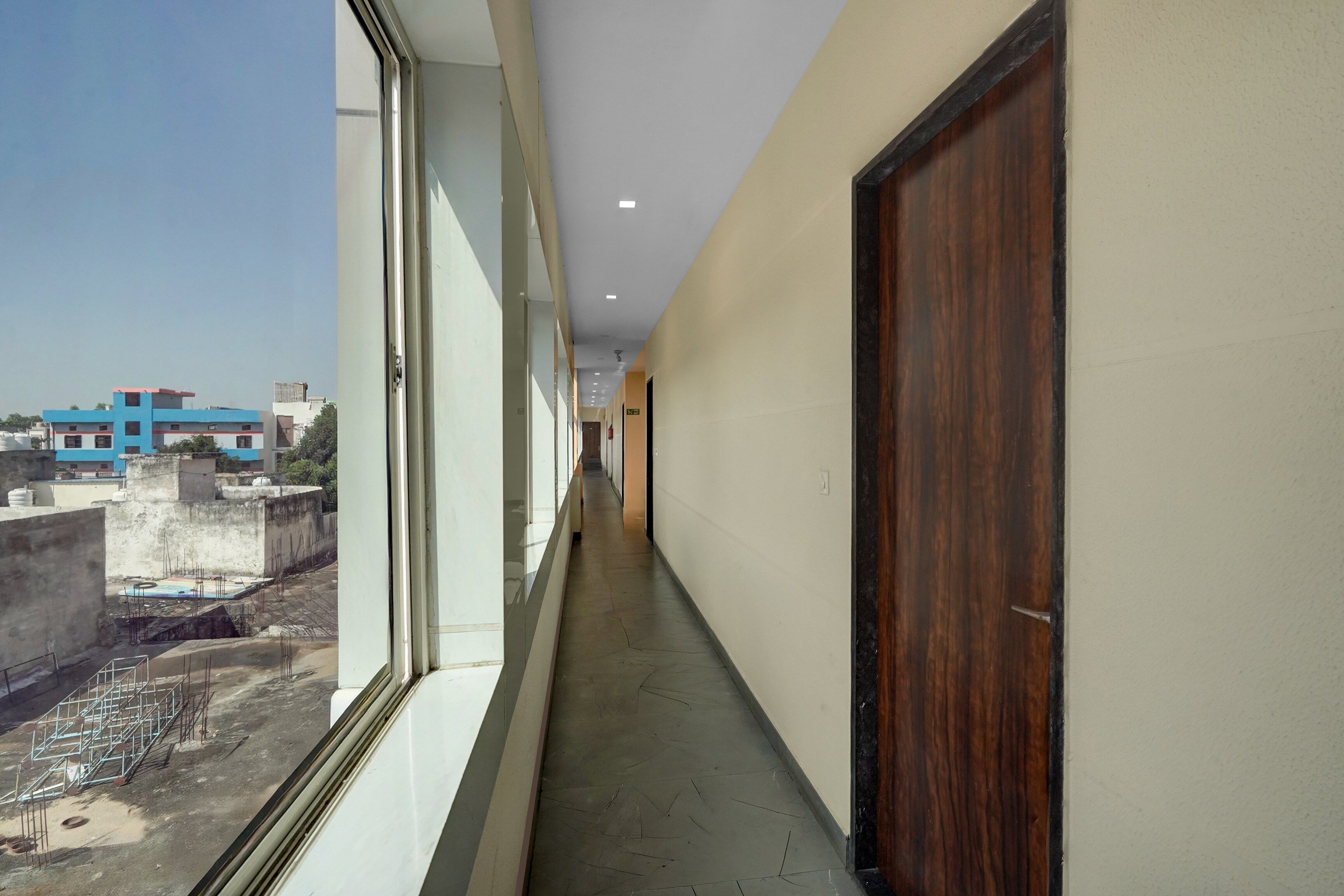 Um corredor com vista para o exterior, uma porta de madeira e uma janela.