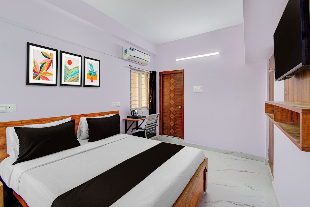 Quarto com cama, escrivaninha, cadeira, televisão e obras de arte na parede.